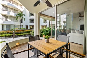 Quarto de hotel moderno com varanda, área de refeições com mesa e cadeiras, e sala de estar com sofá e televis ão.