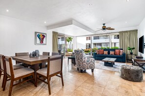 Uma sala de estar espaçosa com uma mesa de jantar, cadeiras, um sofá e uma televisão.