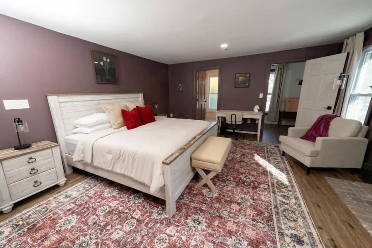 Quarto com cama, mesa de cabeceira, cadeira e escrivaninha.