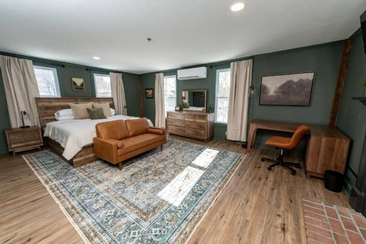Quarto com cama, penteadeira de madeira, escrivaninha e uma cadeira.