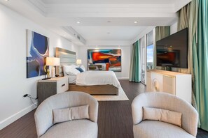 Quarto de hotel moderno com uma cama, duas poltronas, uma escrivaninha e obras de arte nas paredes.