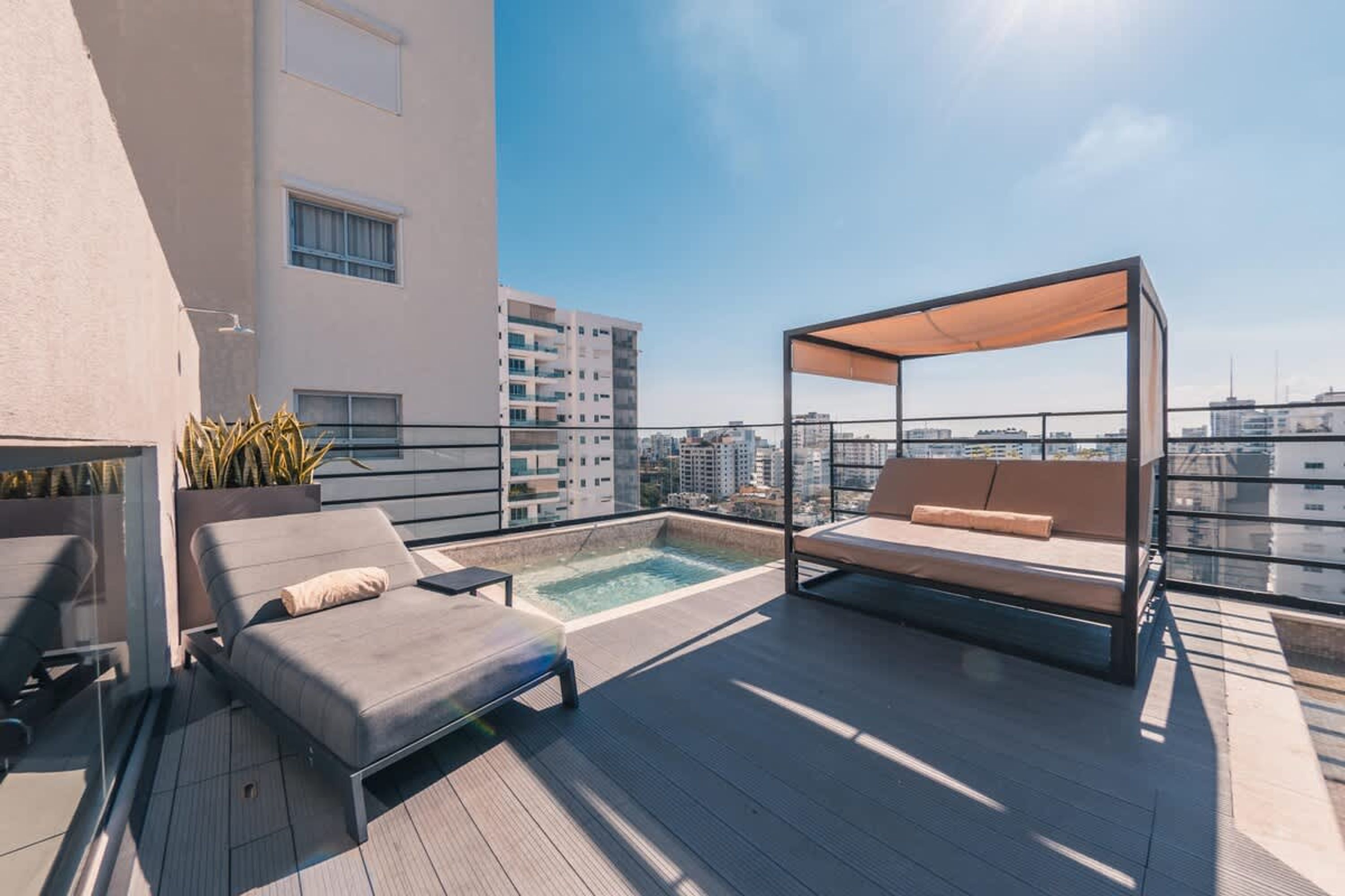 Terraço no telhado com piscina, espreguiçadeiras e área de estar coberta.