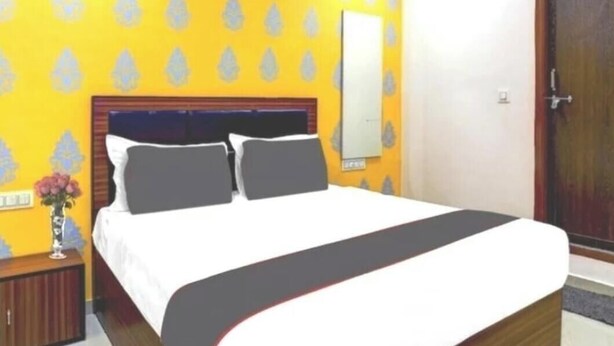 Um quarto com uma cama, mesa de cabeceira, espelho e porta.