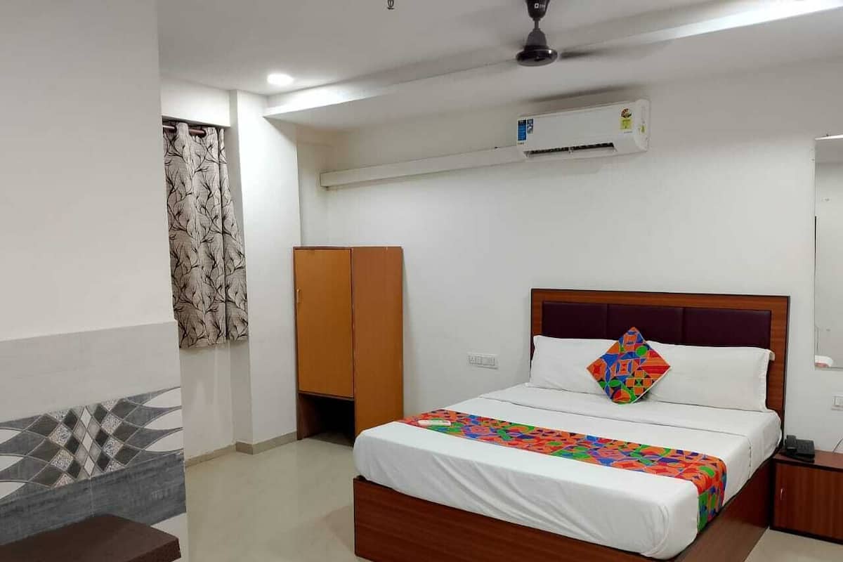 Um quarto com cama, guarda-roupa, escrivaninha e ar condicionado.