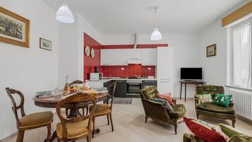 Uma sala moderna com área de jantar, cozinha e televisão.