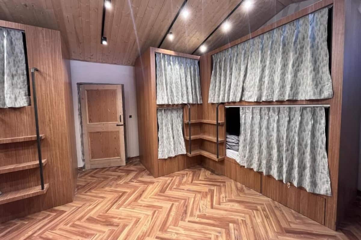Quarto com paredes de madeira, piso em padrão herringbone e estantes embutidas com cortinas.