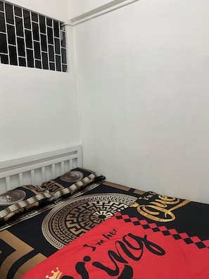 Quarto com cama, janela com grades e radiador.