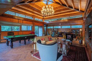 Um quarto amplo com mesa de bilhar, um sofá e um lustre.