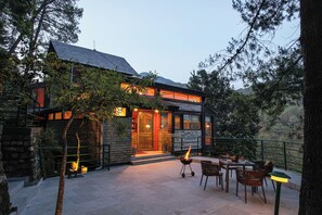 Uma casa moderna com fachada de pedra, um deck de madeira e um espaço para fogueira.