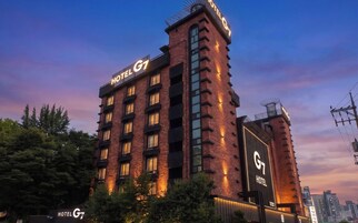 Hotel com placa G7 bem visível, vários andares e fachada de tijolos.