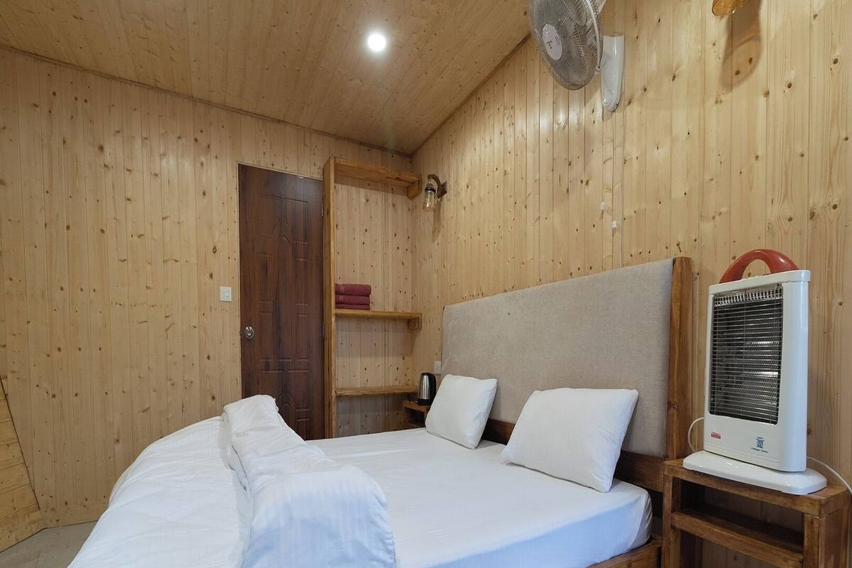 Quarto de madeira com uma cama, um aquecedor e uma porta.