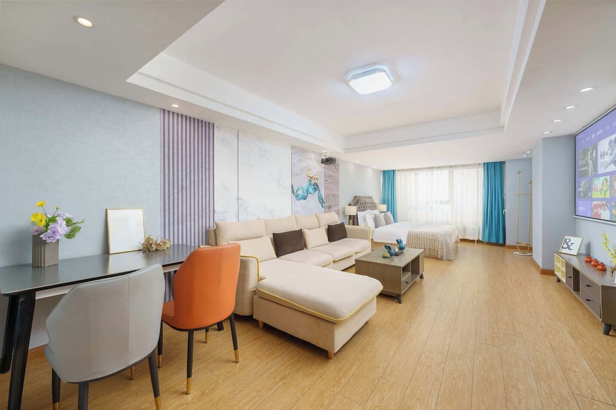 Uma sala de estar moderna com sofá, banqueta, mesa de jantar e cadeiras.