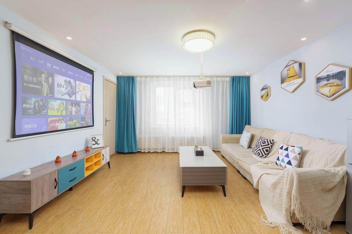 Uma sala de estar moderna com televisão de tela plana, um sofá, uma mesa de centro e um aparador.