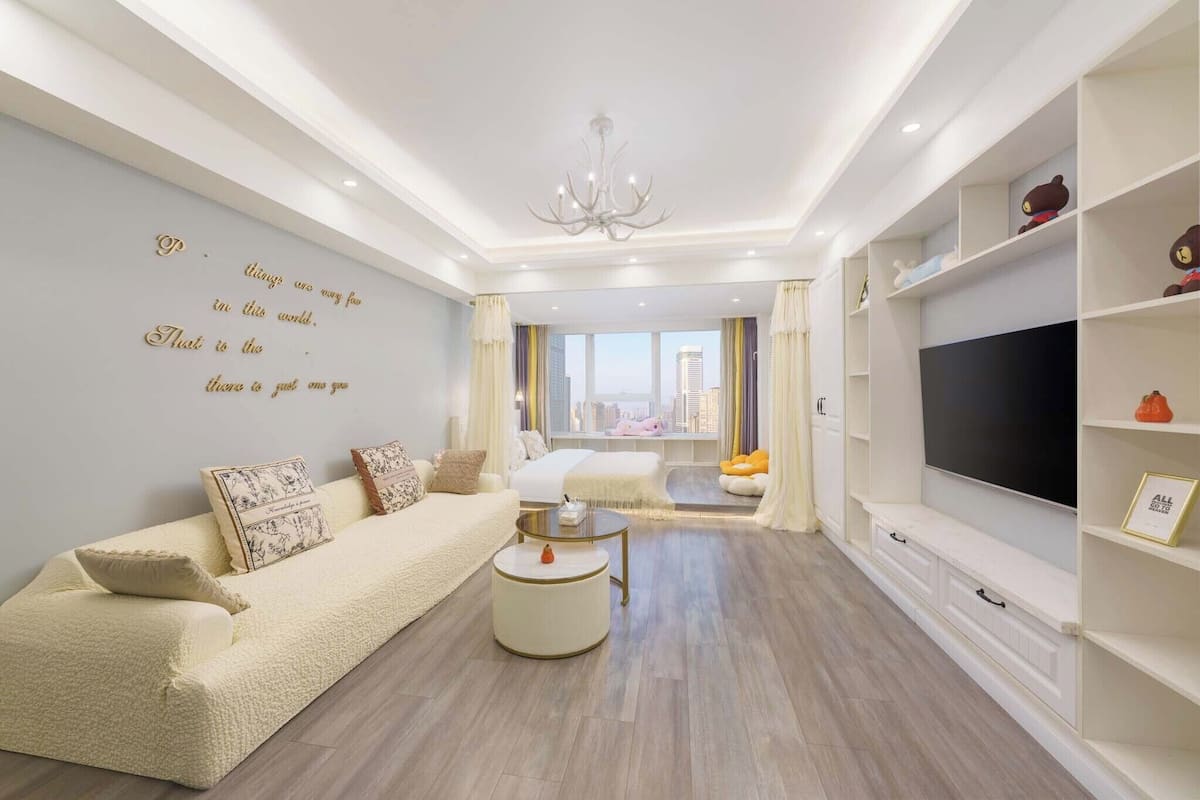 Uma sala de estar moderna com sofá, mesa de centro, TV e vista para a cidade.