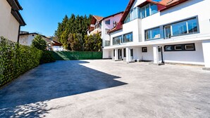 Um edifício residencial moderno com entrada coberta, janelas grandes e cerca verde.
