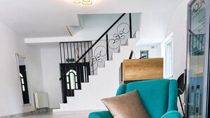 Uma sala de estar moderna com uma poltrona verde-água, uma mesa de centro de madeira e um aparador de vidro com um objeto decorativo.