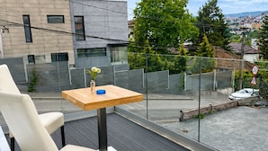 Varanda com mesa e cadeiras, vista para a cidade e placa de limite de velocidade.