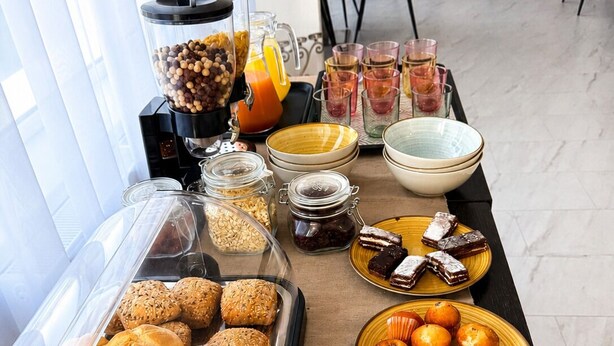 Buffet de café da manhã com pães, bolos e bebidas.