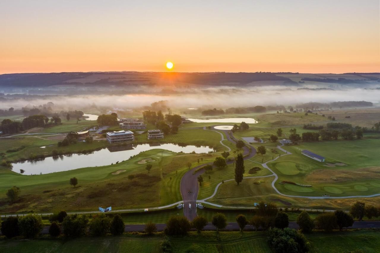 Um campo de golfe com lago, edifícios e uma estrada.