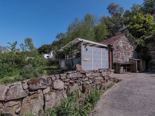 Um muro de pedra, uma cerca de metal com padrão e um edifício com telhado de azulejos.