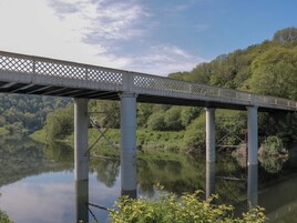 Uma ponte sobre um rio calmo, com vegetação exuberante em ambas as margens.