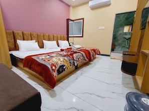 Quarto de hotel com uma cama, cabeceira de madeira, banheiro com parede de mármore verde e piso de mármore.