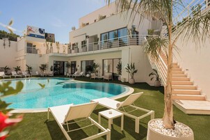 Um hotel moderno com piscina, cadeiras de lounge e uma escadaria.
