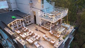 Um terraço no telhado com área de estar externa, espaço coberto e luzes pendentes.