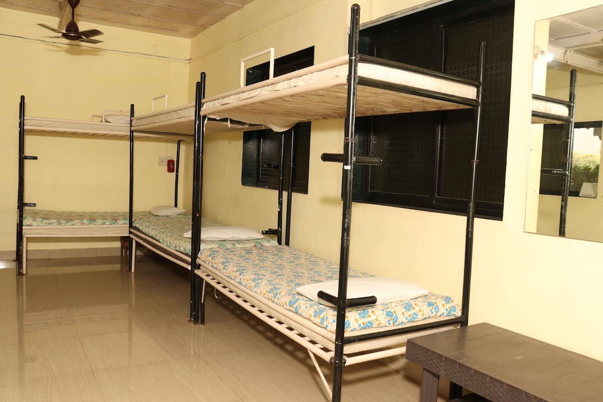Quarto em dormitório com beliches, ventilador de teto e janela com vista.