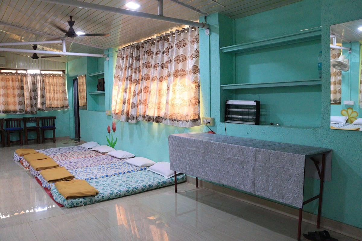 Quarto com cama, mesa, cadeiras e ventilador de teto.