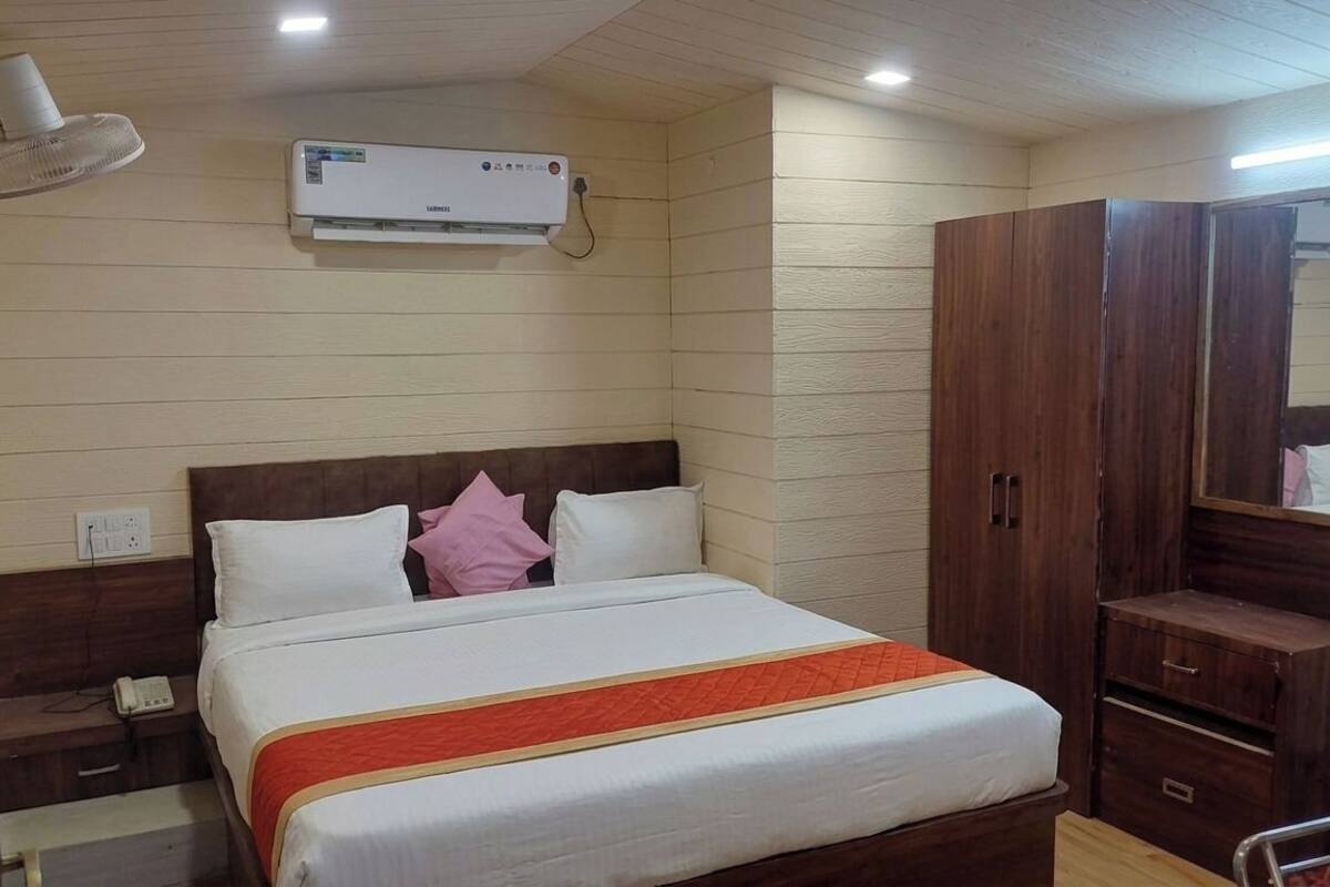 Quarto com cama, mesa de cabeceira, luminária, armário e ar condicionado.