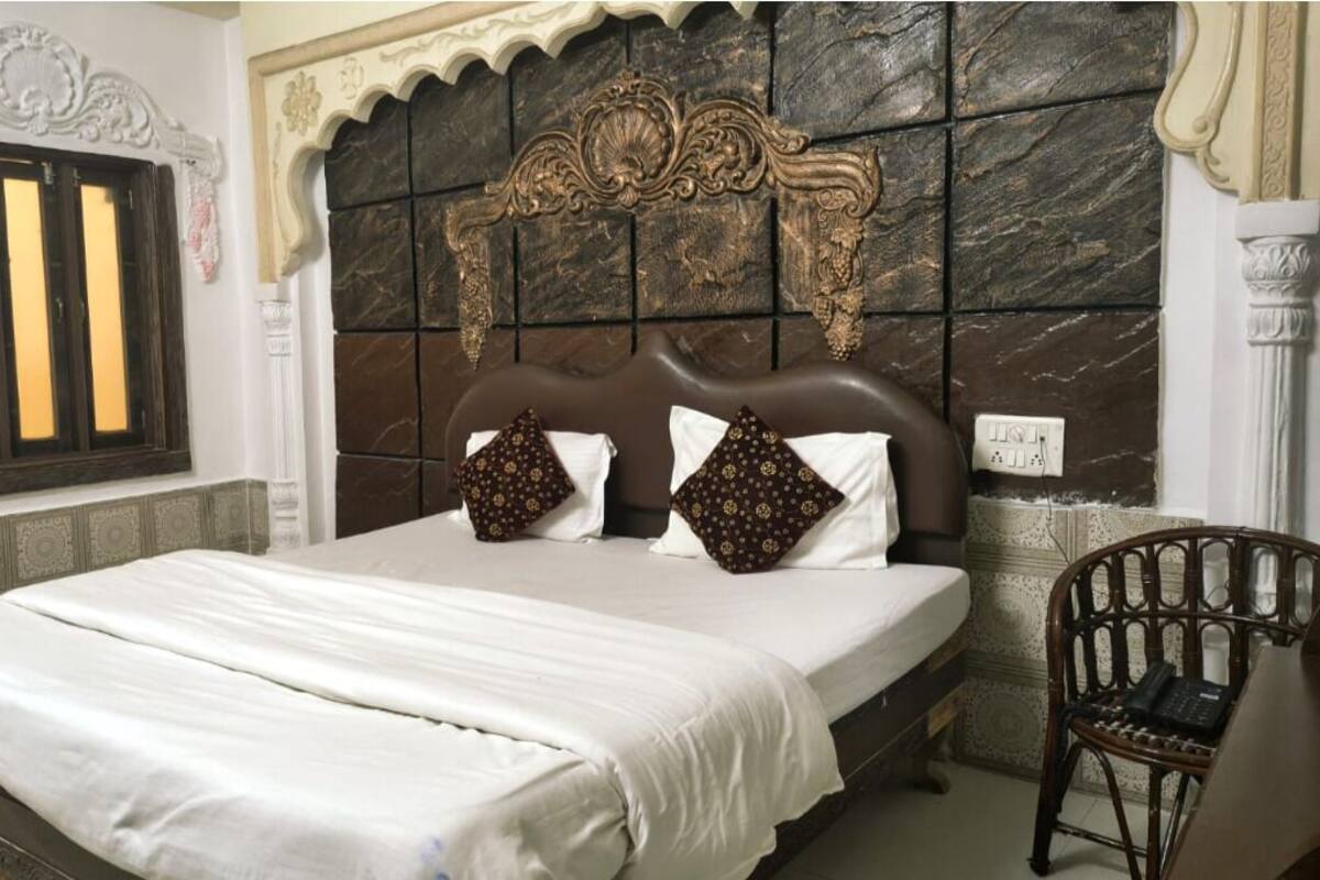 Um quarto com uma cama, uma cadeira e um painel decorativo na cabeceira.