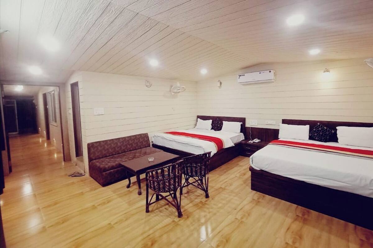 Quarto com duas camas, um sofá, uma mesa e uma cadeira.