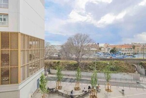 Um edifício moderno com um pátio, área de estar externa e vista para a paisagem urbana.