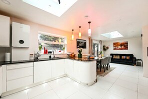 Uma cozinha moderna com ilha central, armários brancos e iluminação pendente.