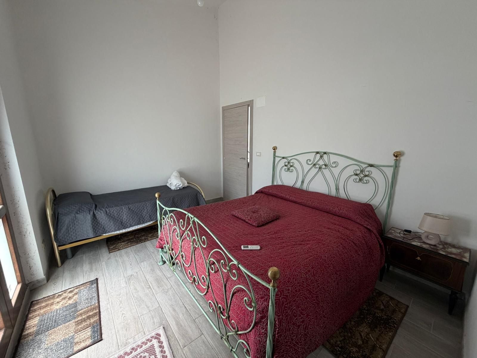 Quarto com uma cama de solteiro, mesa de cabeceira e uma pequena janela.