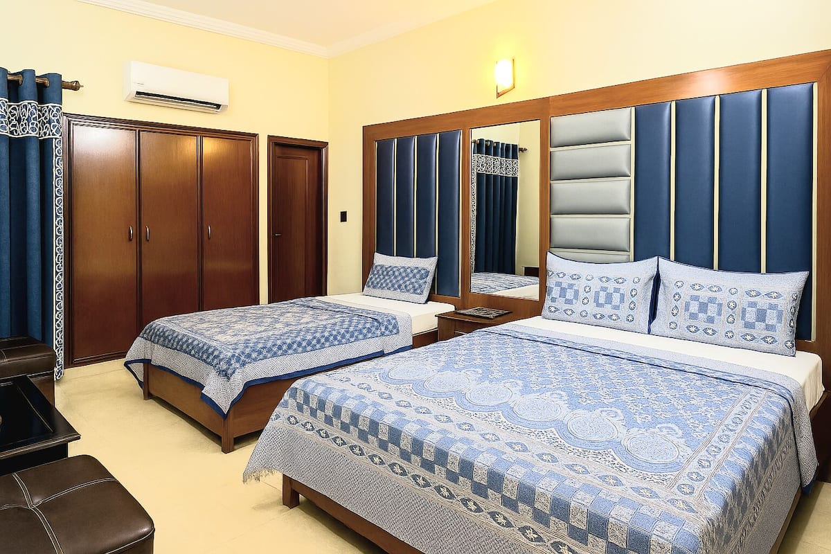 Quarto de hotel com duas camas, um guarda-roupa, um espelho e um ar condicionado.