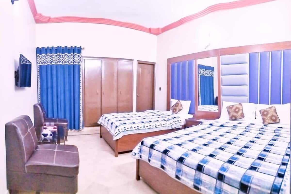 Quarto com duas camas, um sofá, uma escrivaninha e um guarda-roupa.