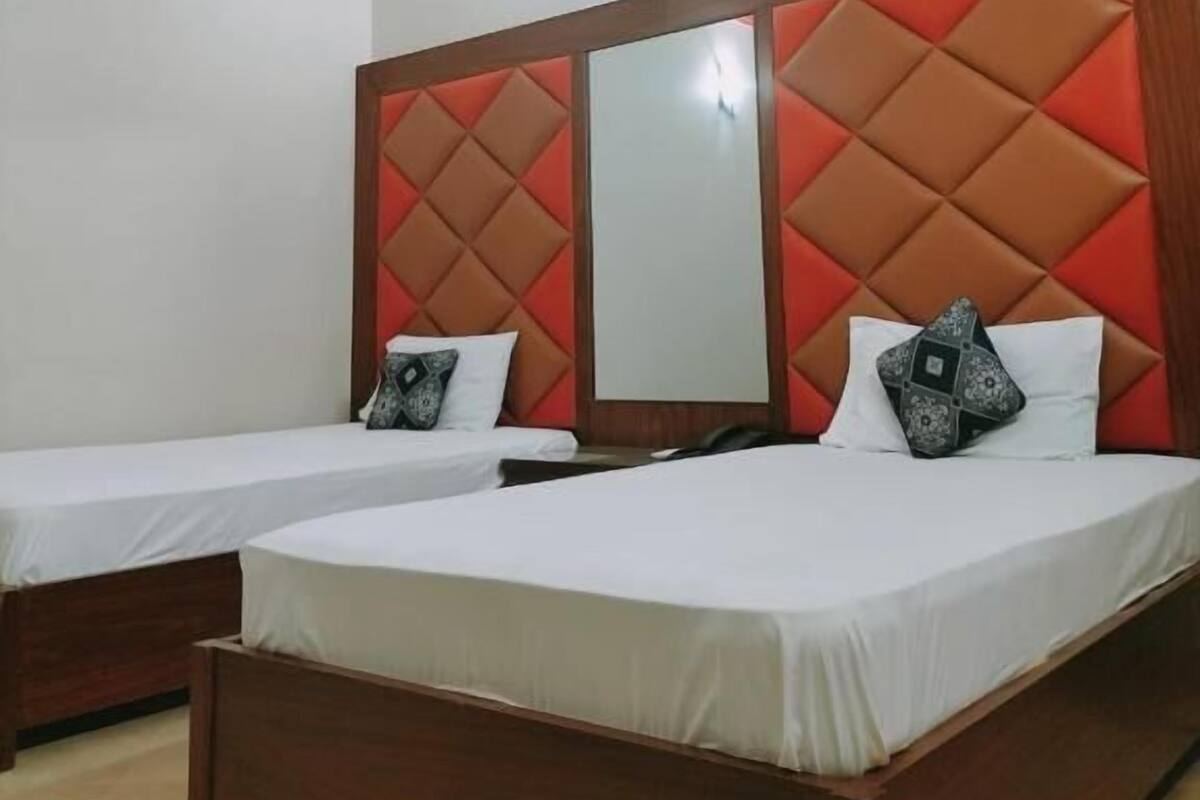 Quarto de hotel com duas camas de solteiro, um ventilador de teto e um espelho grande sobre as camas.