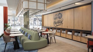Restaurante moderno com sofá verde, várias mesas e parede de madeira com um letreiro.