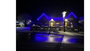 Uma casa com telhado iluminado em azul e cerca de madeira na frente.