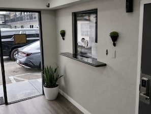 Interior moderno com uma planta em vaso, uma prateleira com relógio e uma porta que dá para o exterior.