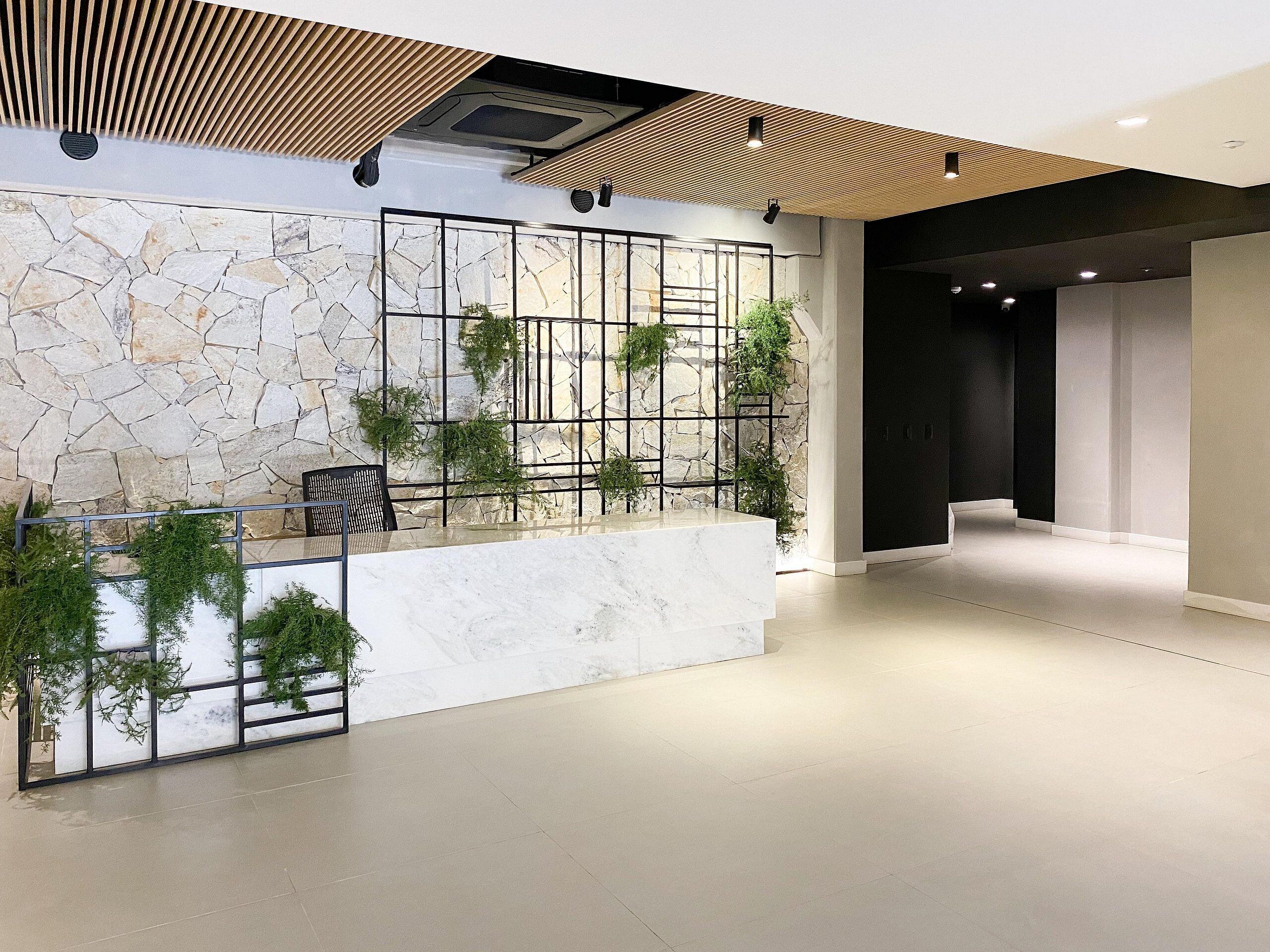 Um lobby moderno com parede de pedra, balcão de recepção e escada.