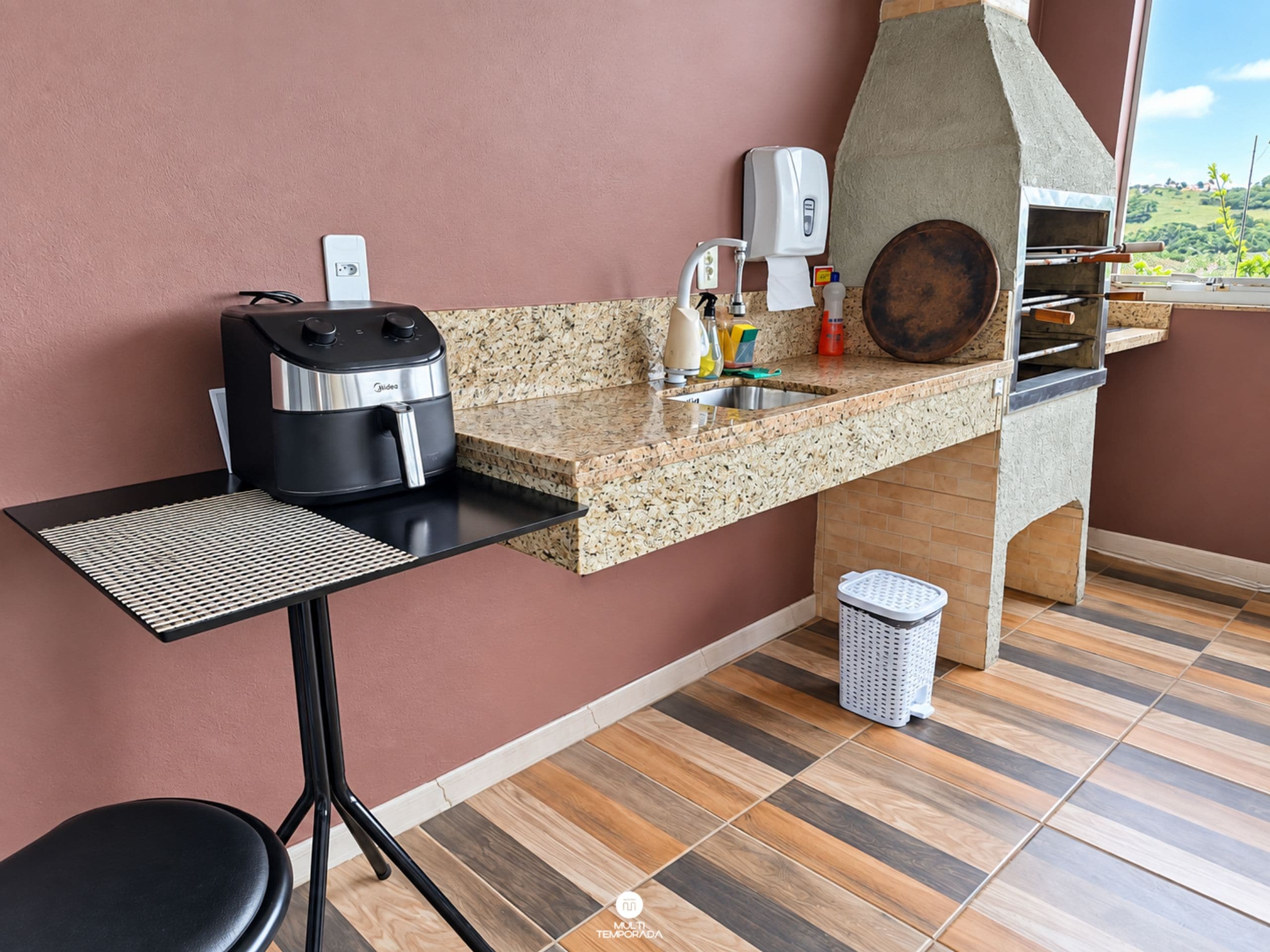 Cozinha compacta com cafeteira, pia e churrasqueira embutida.