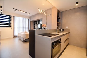 Cozinha moderna com ilha central, forno embutido e iluminação pendente.