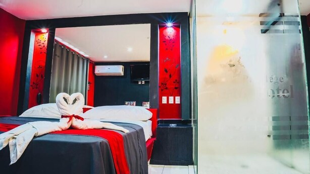 Quarto de hotel com cama, parede decorada em vermelho e porta de vidro.