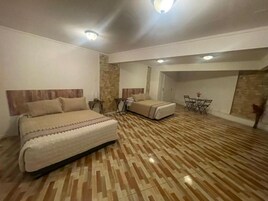 Quarto com uma cama grande, um sofá menor, uma mesa de jantar e uma parede de destaque em pedra.