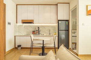 Uma cozinha compacta com geladeira, cafeteira e uma pequena mesa de jantar com cadeiras.