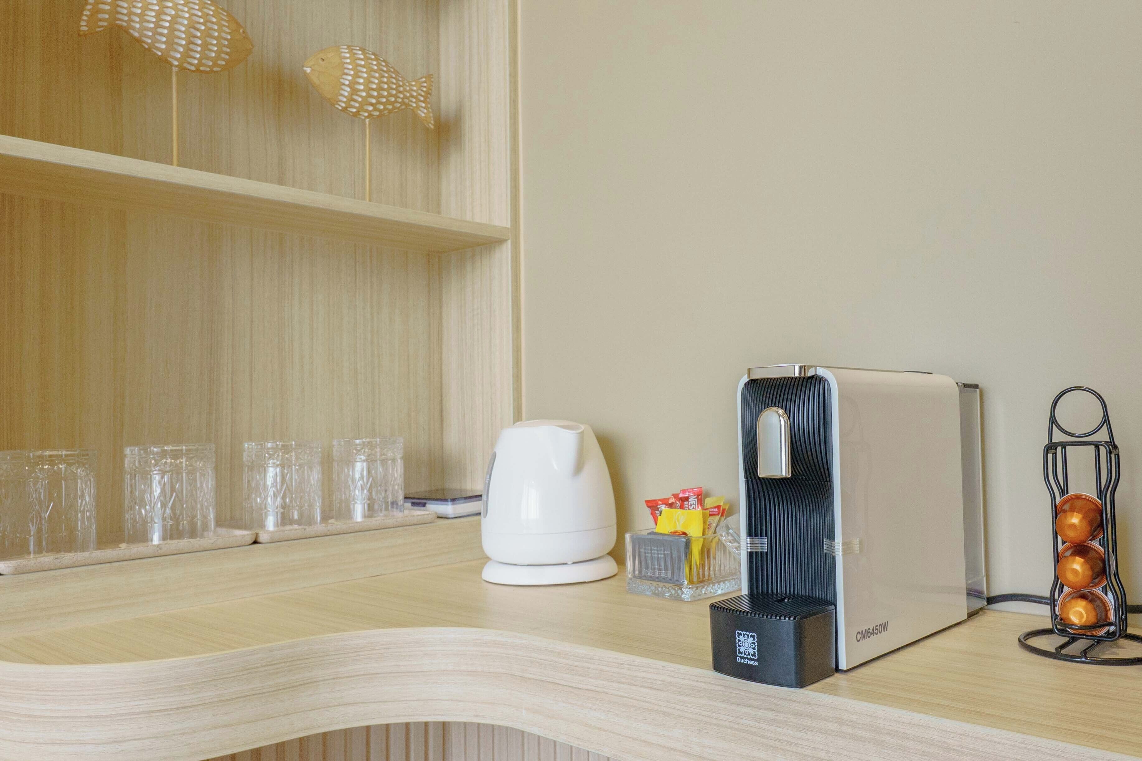 Uma área de recepção de hotel com uma máquina de café, uma chaleira e um tabuleiro com lanches.