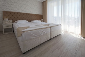 Quarto de hotel com uma cama grande, duas mesas de cabeceira, uma cabeceira e vista para o exterior.
